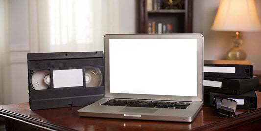 VHS tapes next to a laptop for digital conversion.